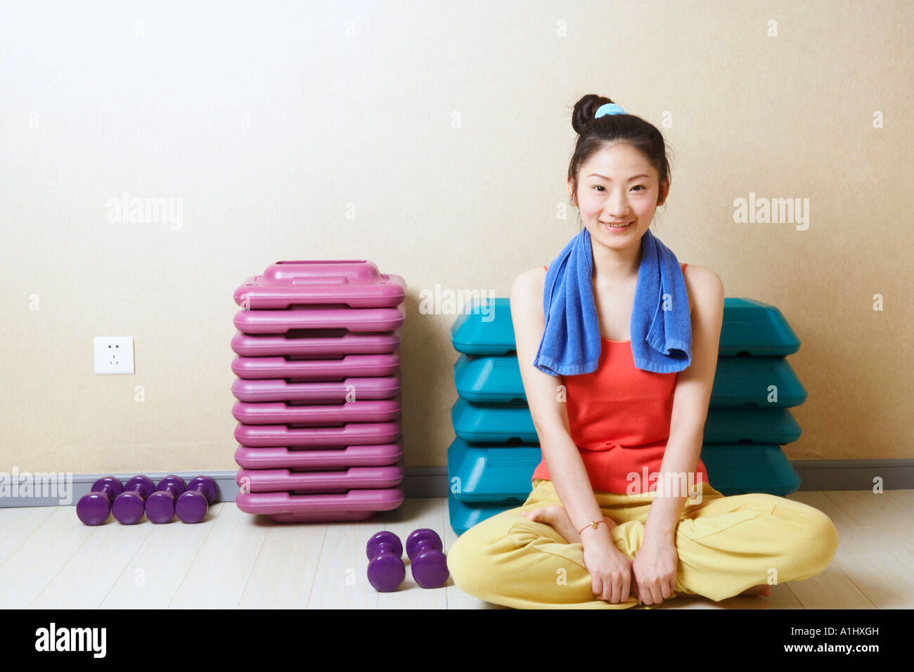 Portrait of a teenage girl sitting in front of stack of aerobic steps ...
