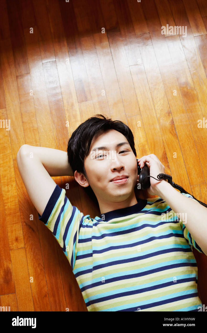 High angle view of a young man talking on the telephone and lying on a ...