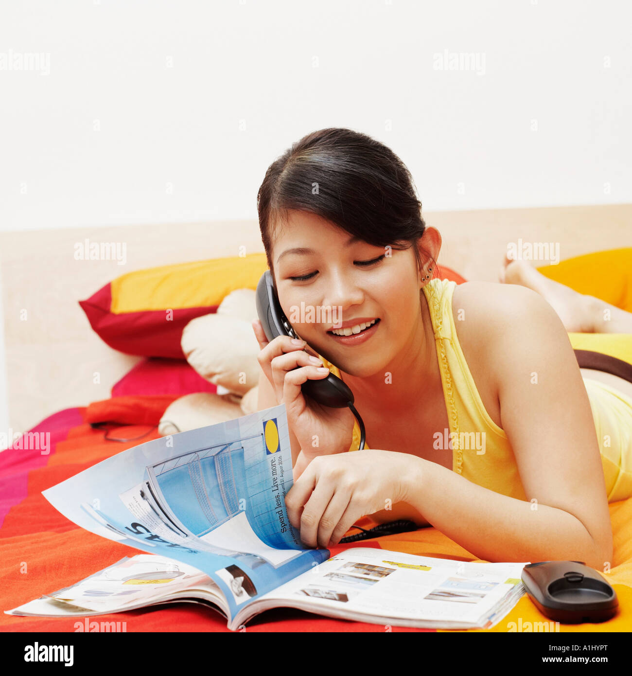 Young woman talking on the telephone and reading a magazine Stock Photo ...