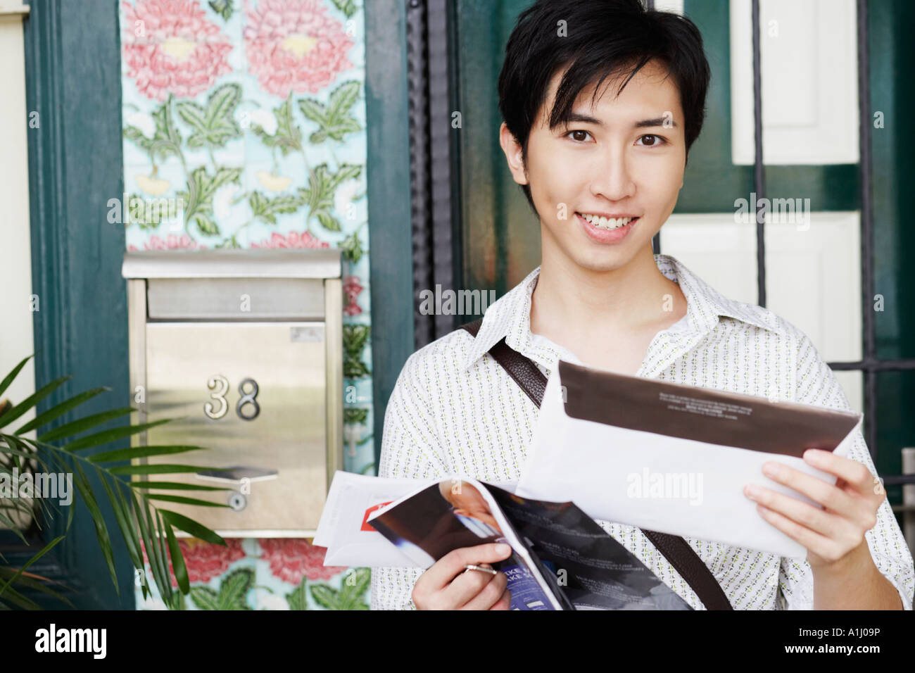 Portrait of a young man holding mail and smiling Stock Photo - Alamy