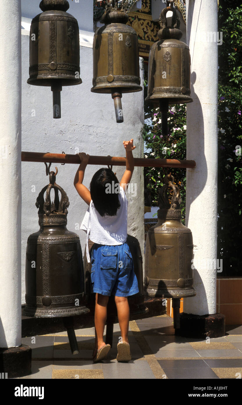 Little girl is rising herself to try to get to the bell. Budist temple ...