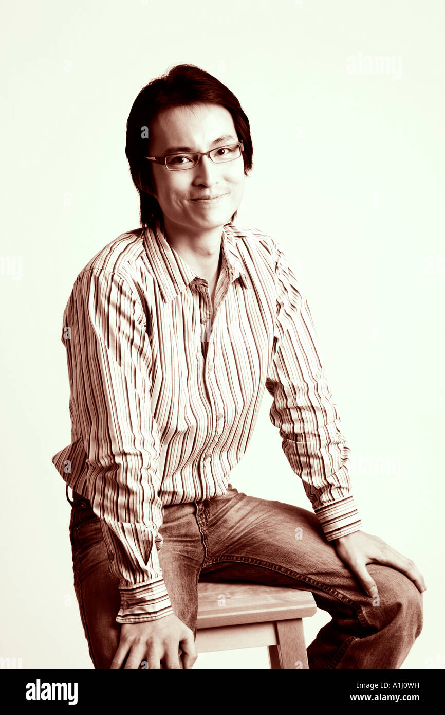 Portrait of a mid adult man sitting on a stool and smiling Stock Photo ...