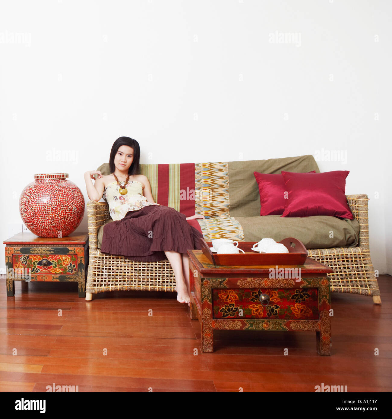 Portrait of a young woman sitting on a couch Stock Photo - Alamy