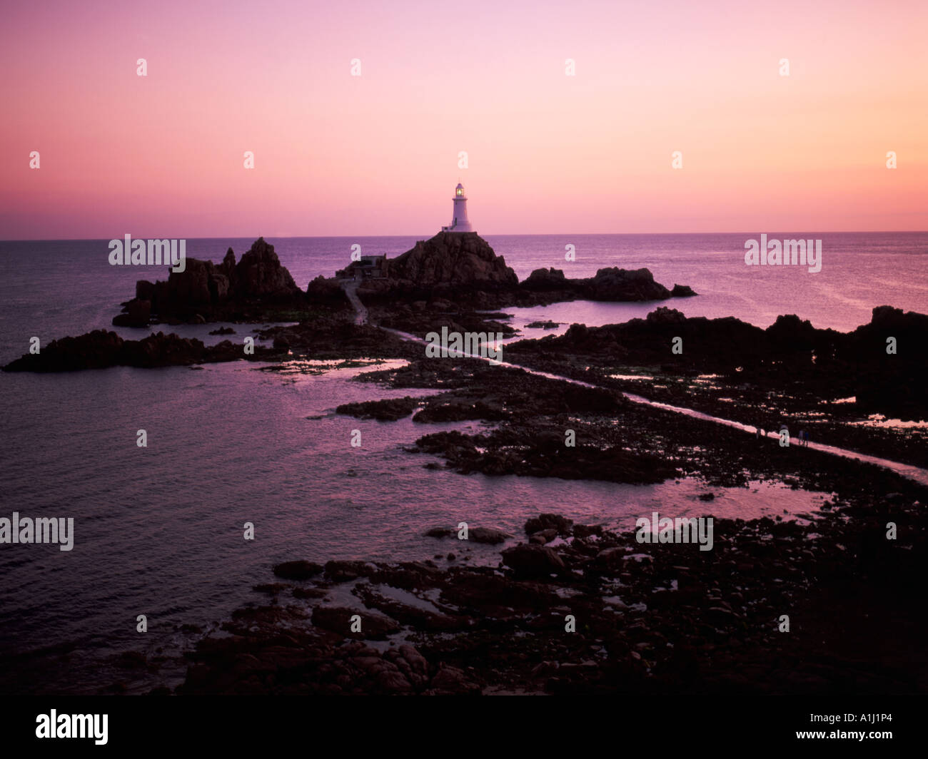 La Corbiere lighthouse at sunset linked to the Jersey mainland at low ...