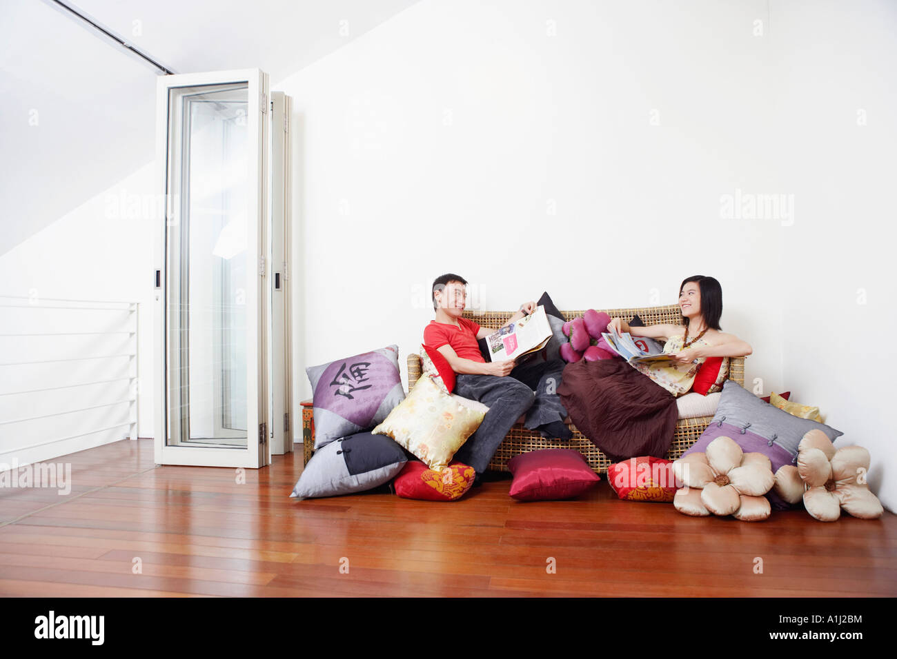 Side profile of a mid adult man with a young woman reclining on a couch ...