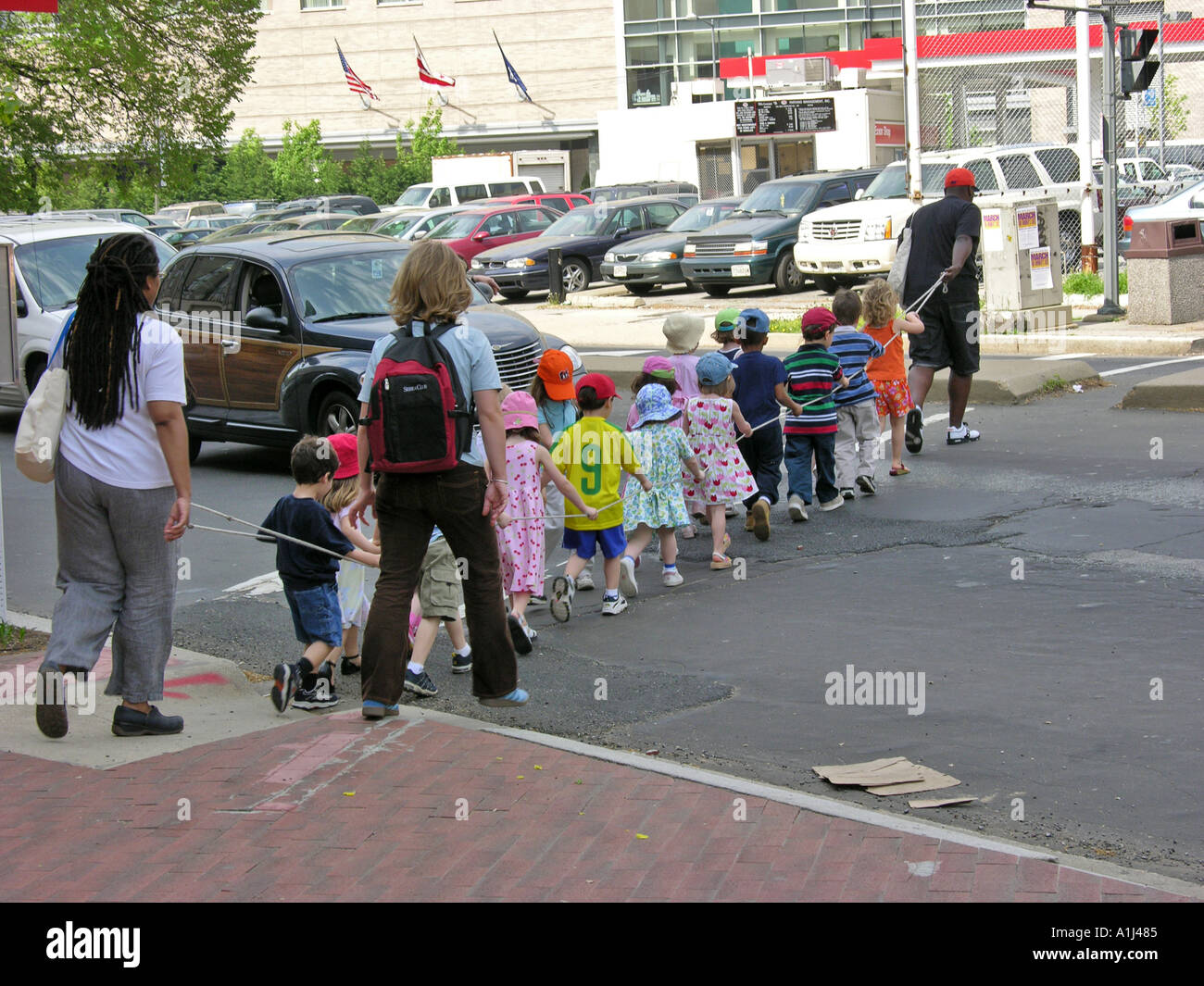 Chaperon adult use ropes to guide student class across a busy downtown ...