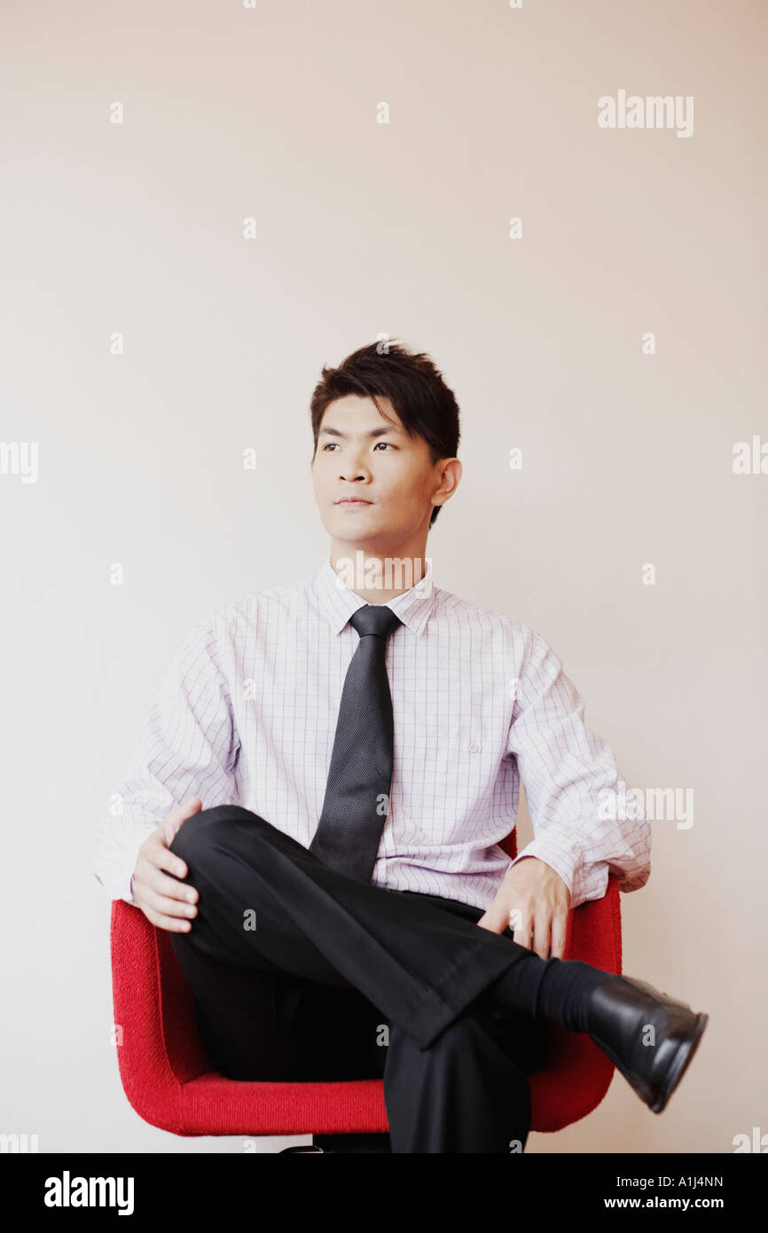 Businessman sitting in an armchair and thinking Stock Photo - Alamy