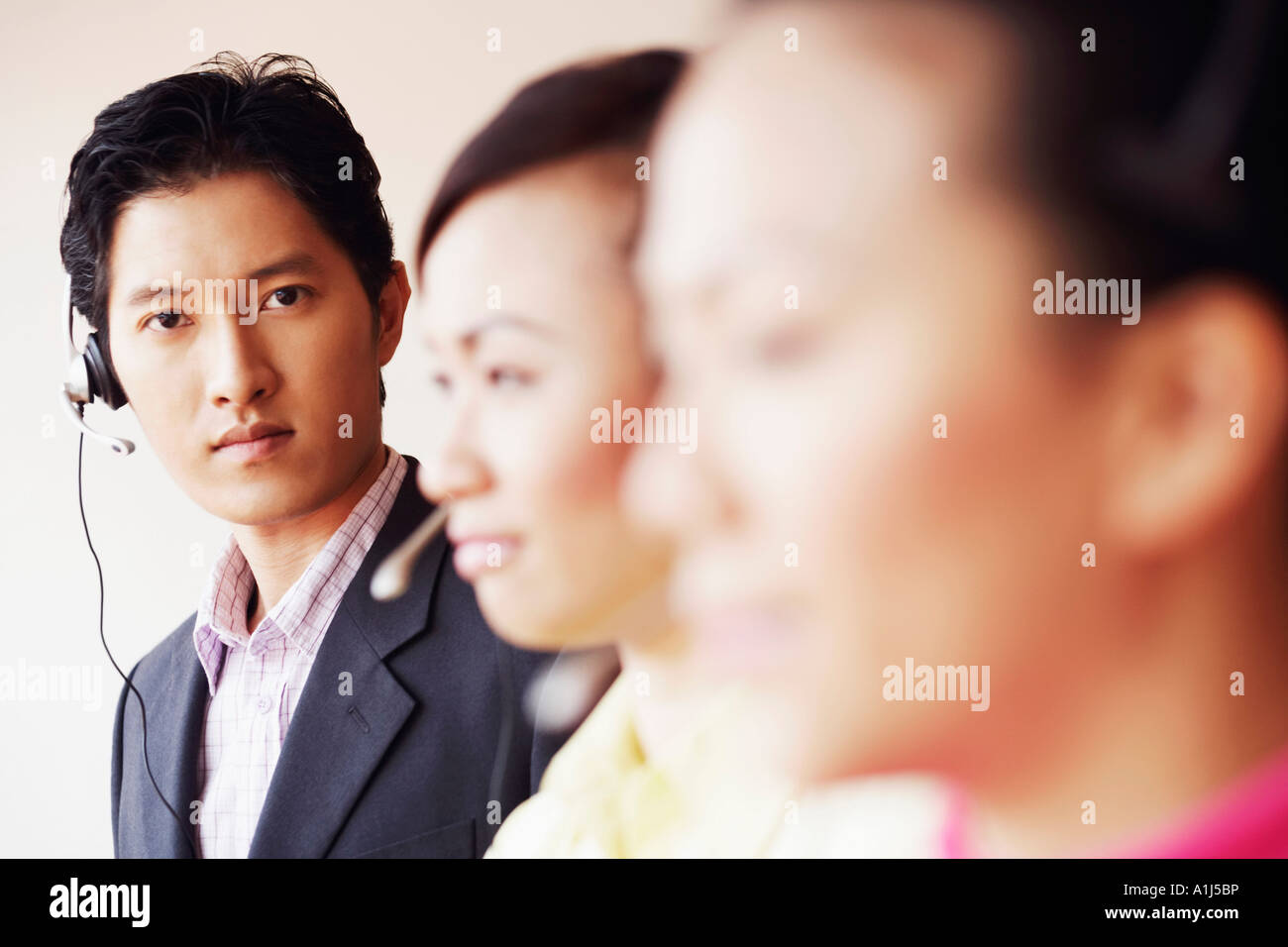 Portrait of a male customer service representative with two colleagues ...