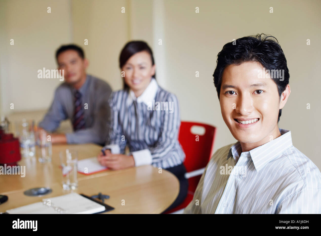 Portrait of a businessman seated at a conference table and smiling with ...