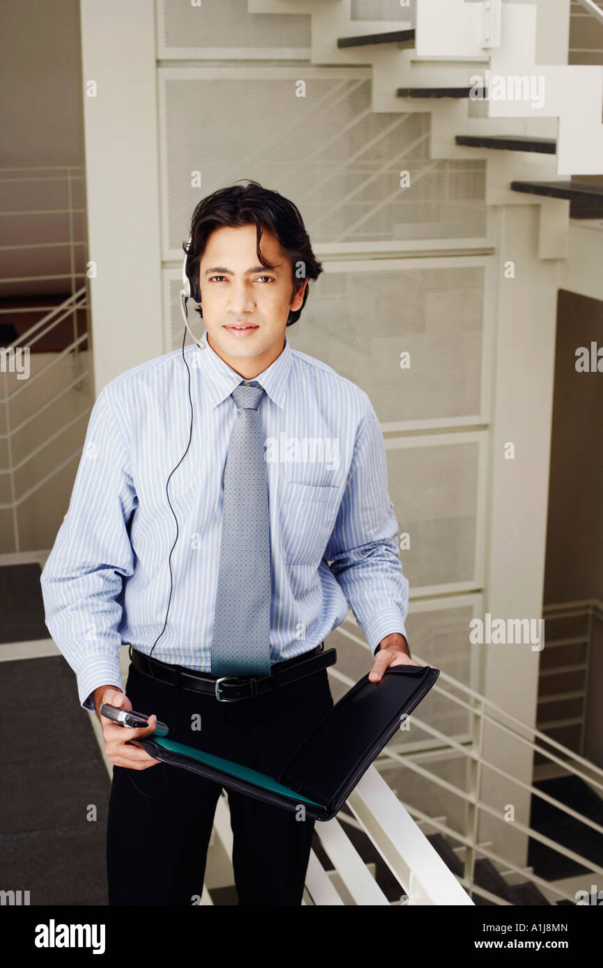 Portrait of a male customer service representative holding a file and a ...
