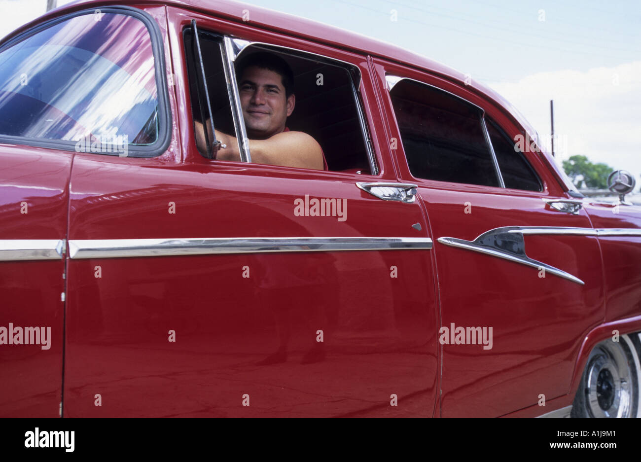 The proud owner in his beautifully kept up red American vintage car in ...