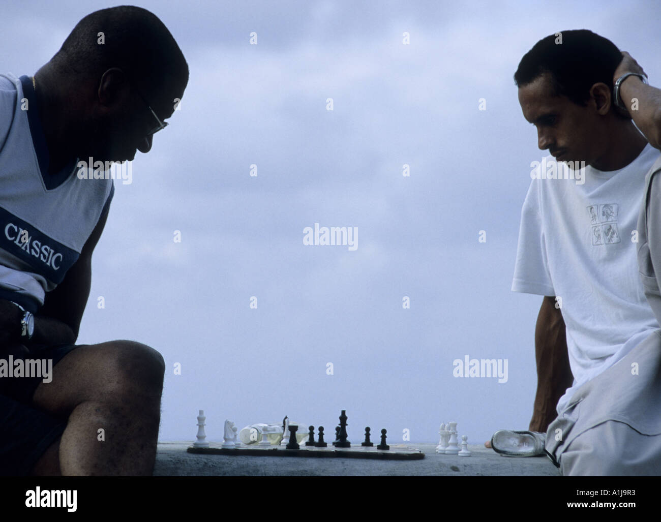 Two men sitting on the seawall of the Malecon, Havana, Cuba, playing ...