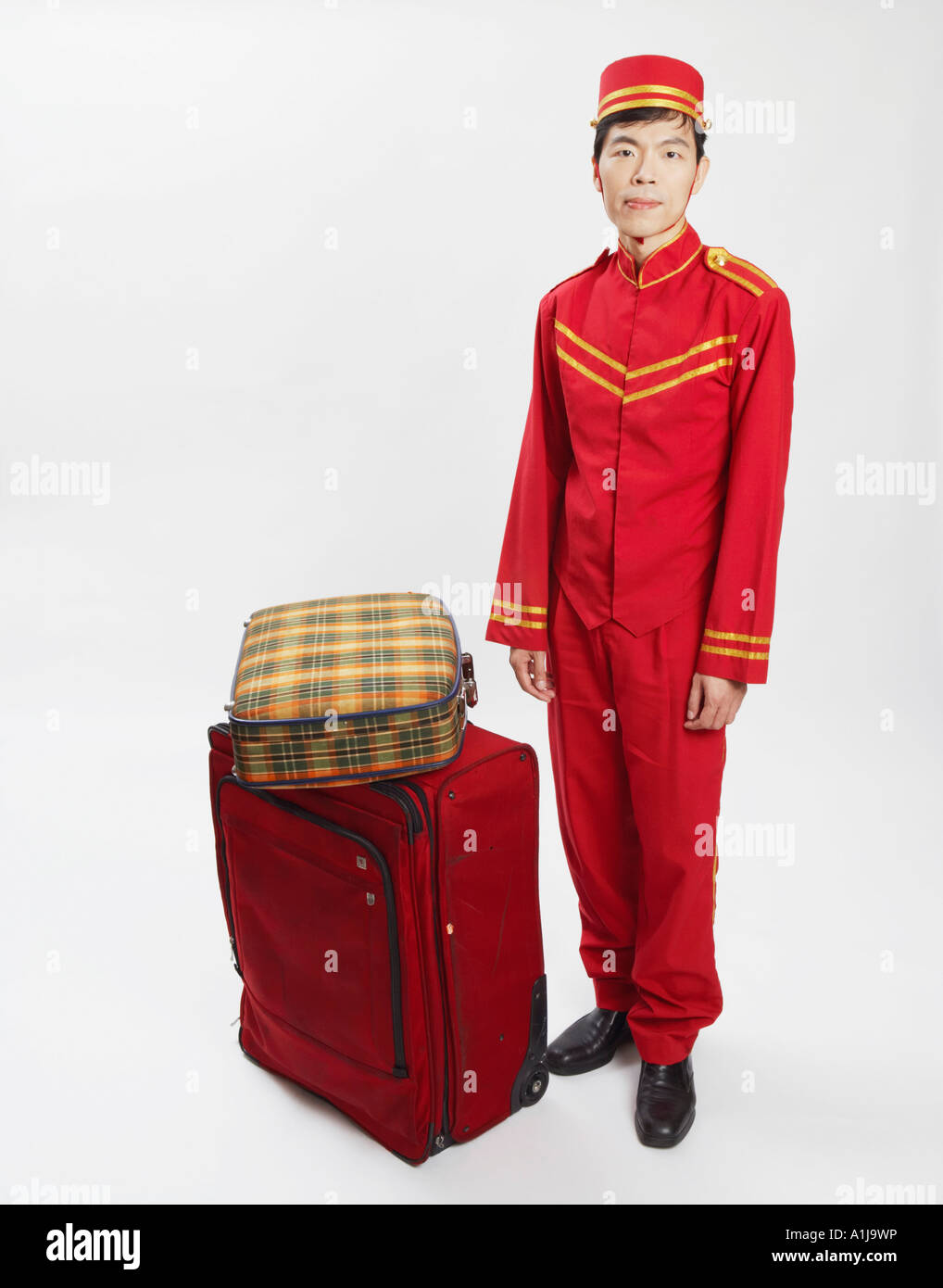 Portrait of a bellhop standing with luggage Stock Photo - Alamy