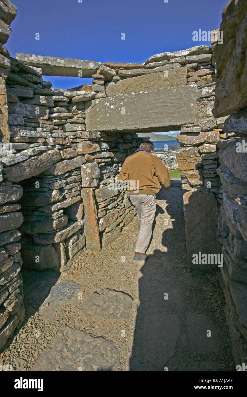 A visitor explores the preserved pre Christian village of the Broch of ...
