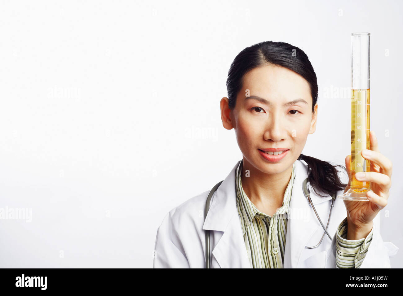 Portrait of a female doctor holding a graduated cylinder and smiling ...