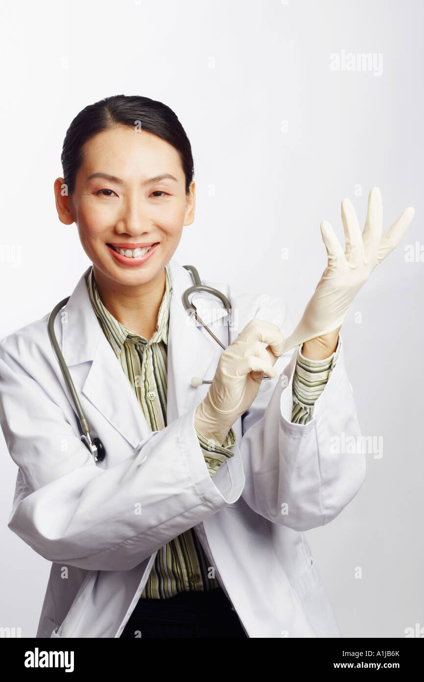 Portrait of a female doctor putting on surgical gloves Stock Photo - Alamy