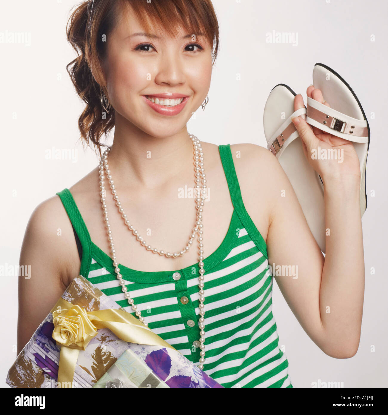 Portrait of a young woman holding a pair of slipper and smiling Stock ...