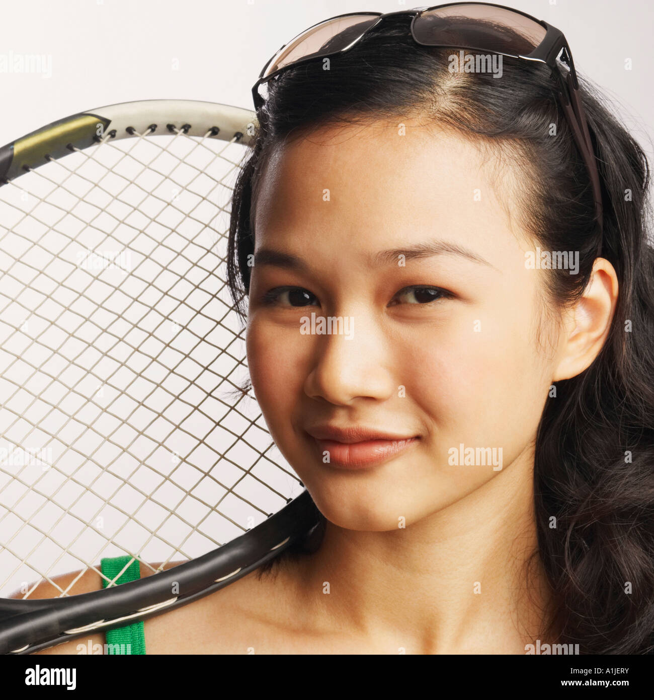Portrait of a young woman holding a tennis racket and smiling Stock ...