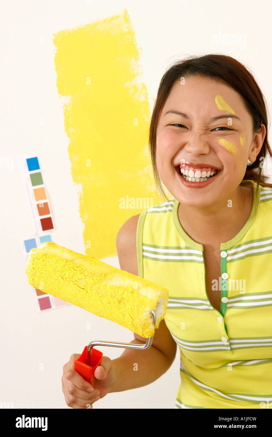 Portrait of a young woman holding a paint roller Stock Photo - Alamy