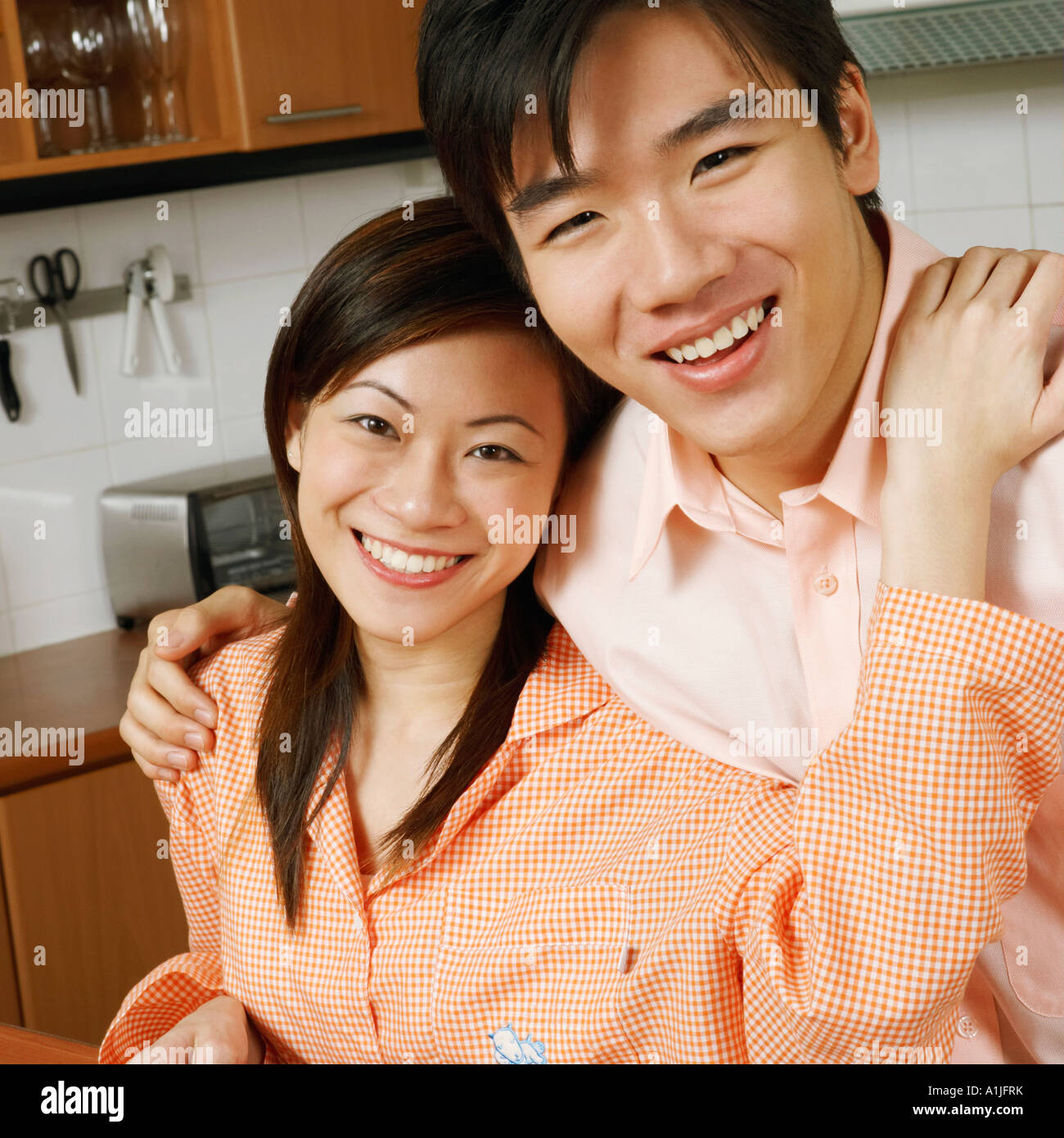 Portrait of a young couple smiling at a kitchen counter Stock Photo - Alamy