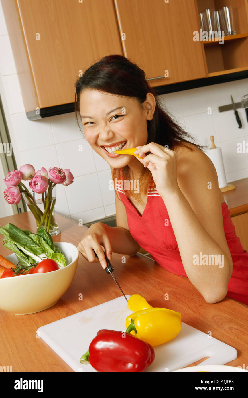 Portrait of a young woman eating a slice of yellow bell pepper at a ...