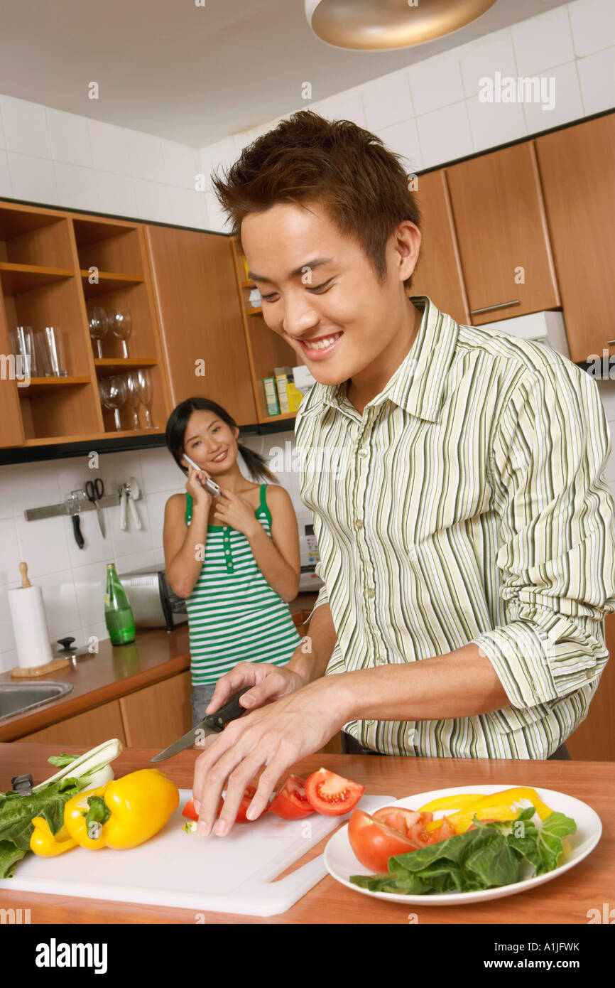 Close-up of a young man cutting vegetables in the kitchen with a young ...