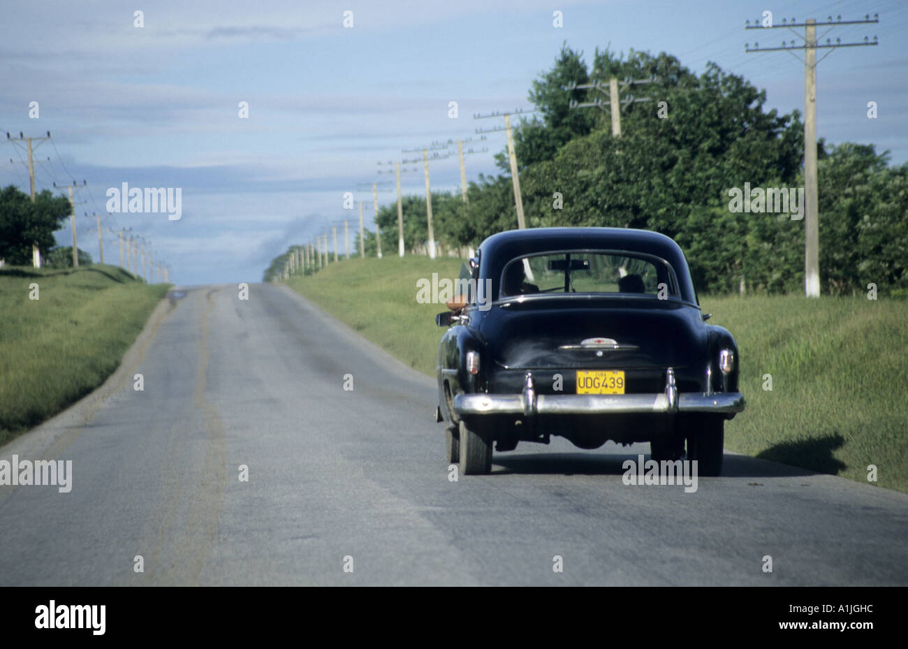 Backview of a black American oldtimer on a provincial tarmac road in ...