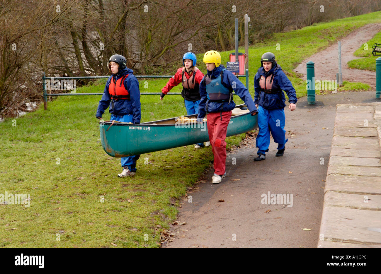 Students showing teamwork while launching an open canoe on the banks of ...