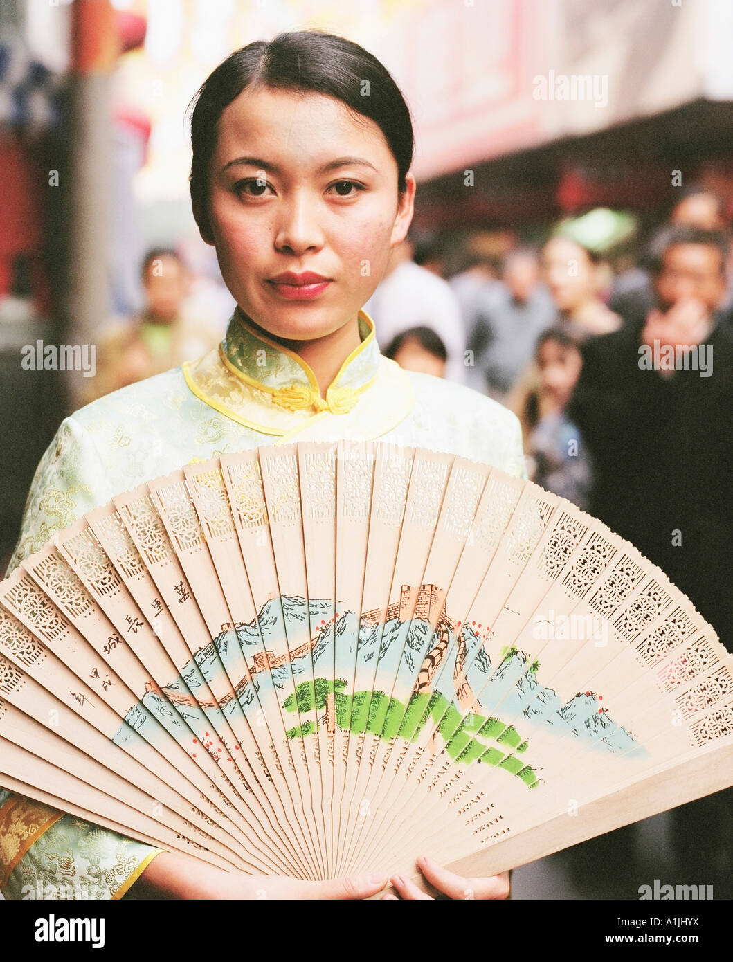 Portrait of a young woman in a traditional dress and holding a fan ...