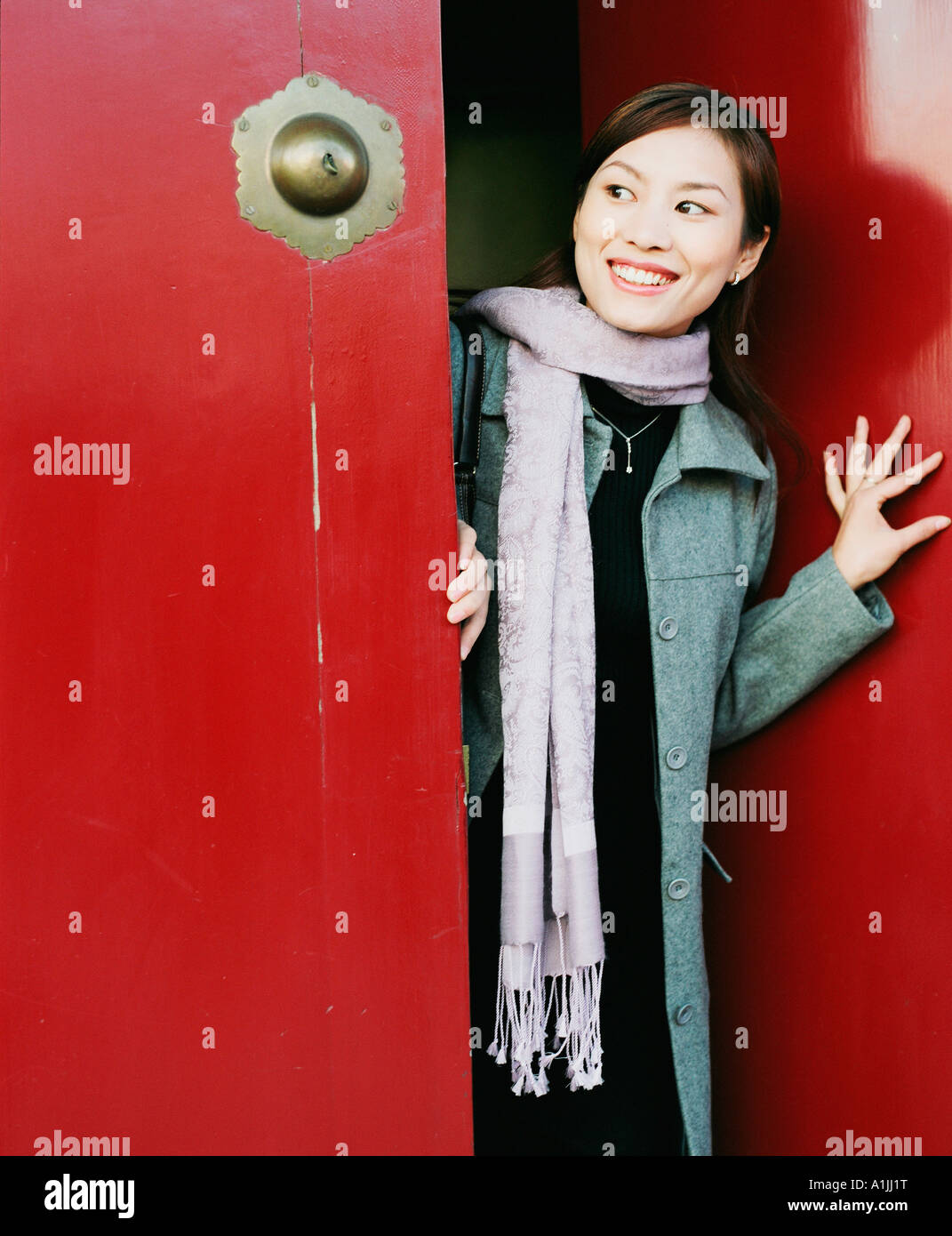 Close-up of a young woman looking out of an open door Stock Photo - Alamy