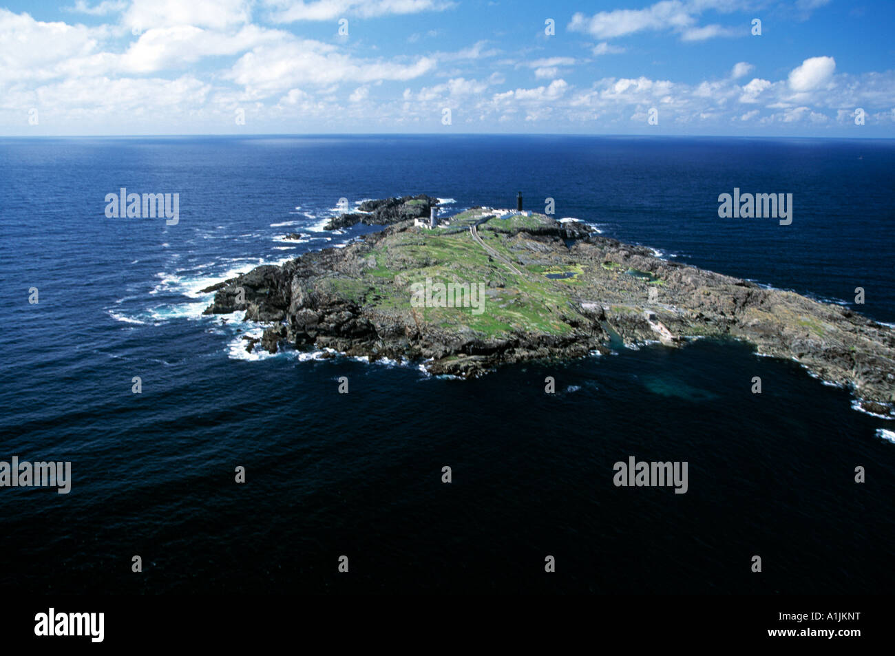 large rocky outcrop jutting into the atlantic ocean with lighthouse off ...