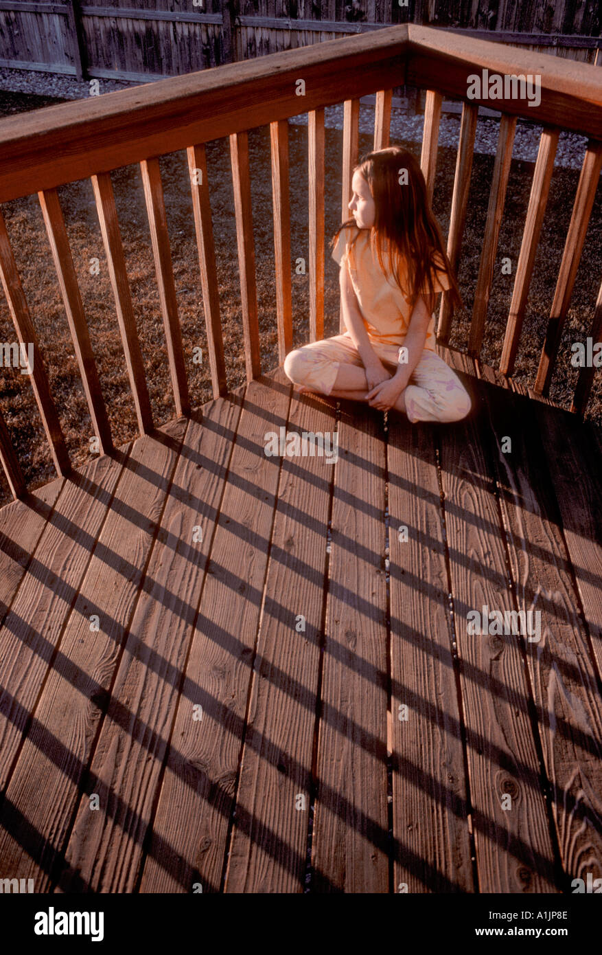 Young girl sitting on a backyard deck Stock Photo - Alamy