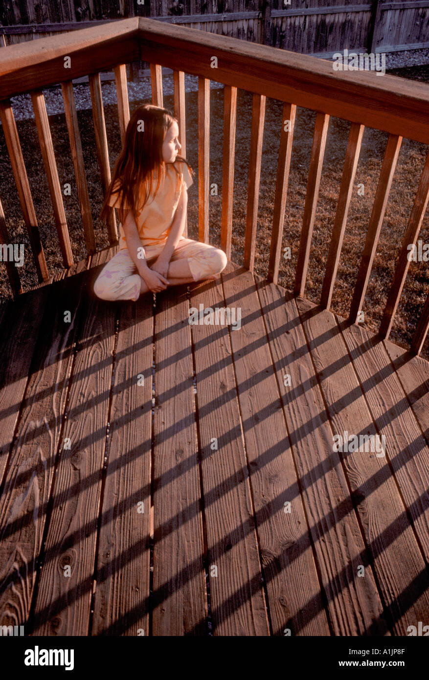 Young girl sitting on a backyard deck Stock Photo - Alamy