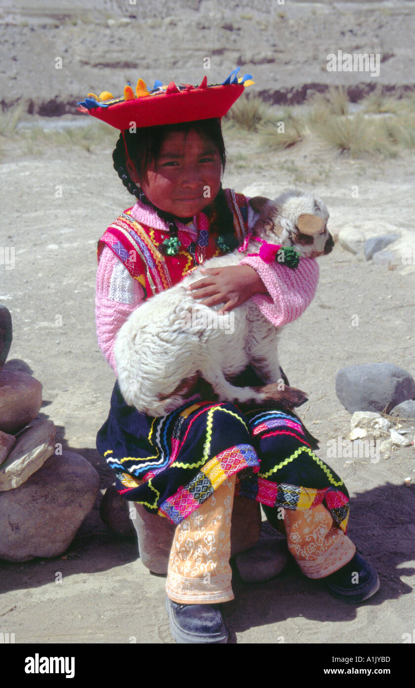 Girl in traditional dress with a baby alpaca in the Colca Canyon region ...