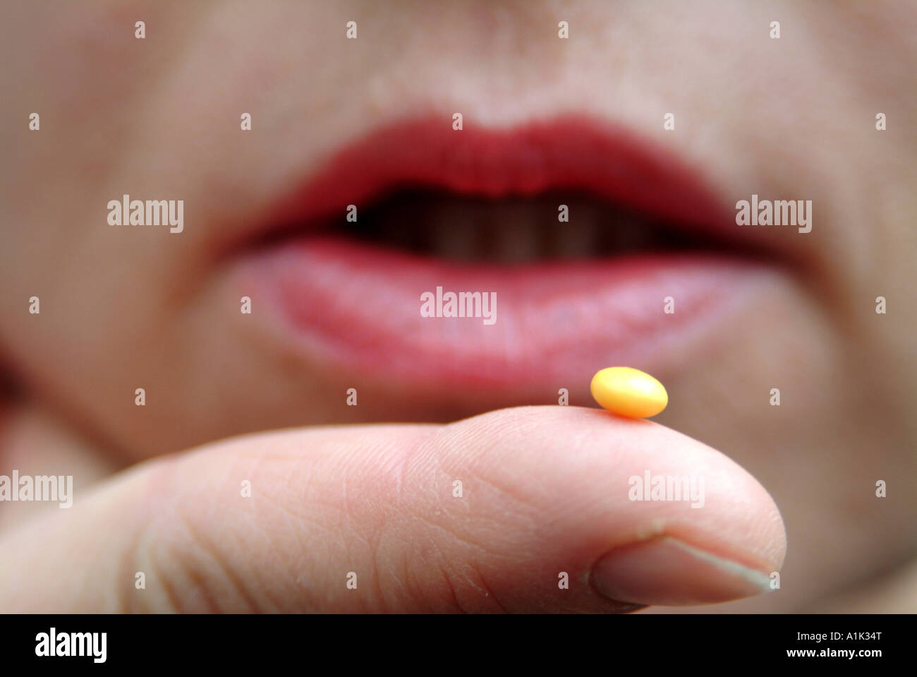 yellow pill on finger Stock Photo - Alamy