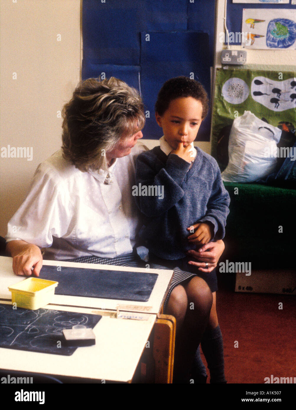 teacher comforting young boy in classroom Stock Photo - Alamy
