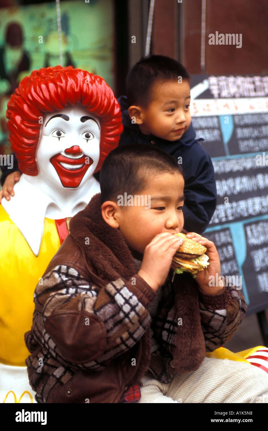 Fat Chinese child eating ham burger sitting on Ronald McDonald ...