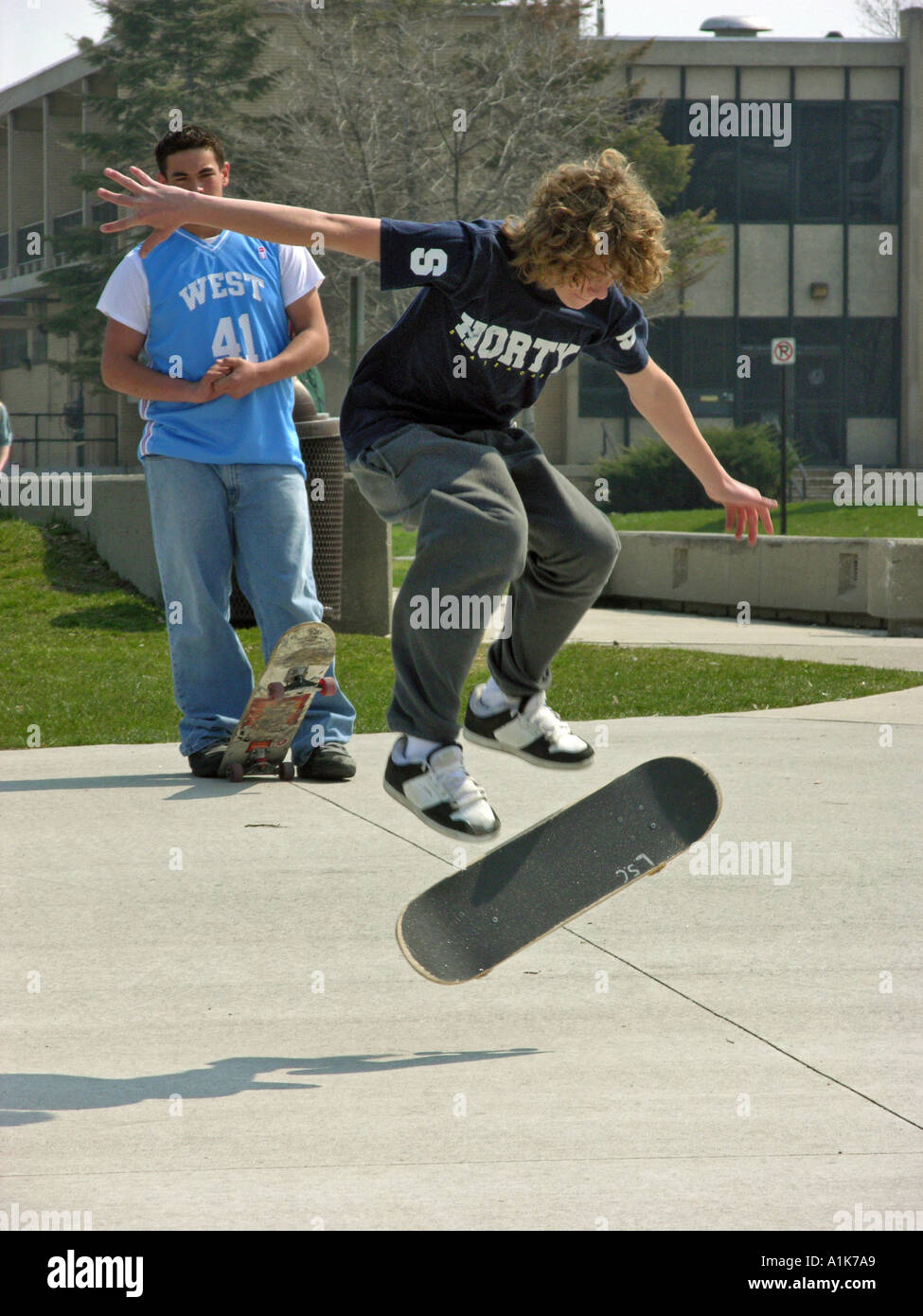 Teen males practice skate board maneuvers at a local public park in ...