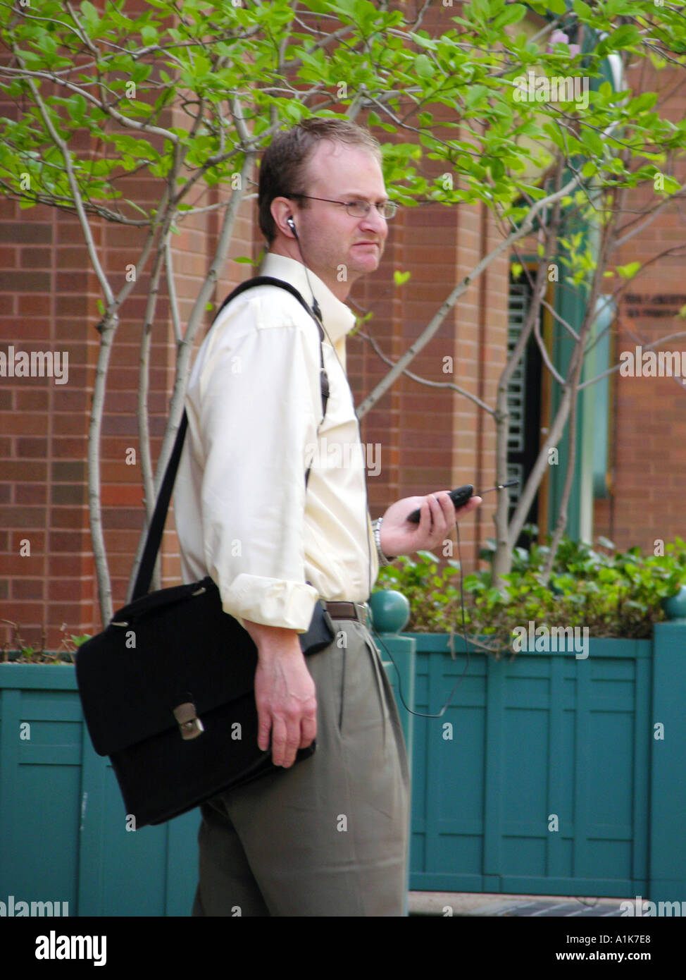 Adult male using cell phone with ear plug Stock Photo - Alamy