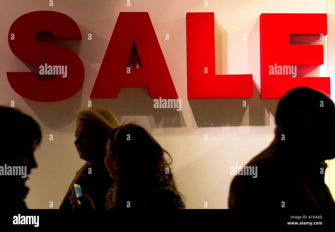 Pedestrians walking by a shop window that shows a big SALE sign Stock ...