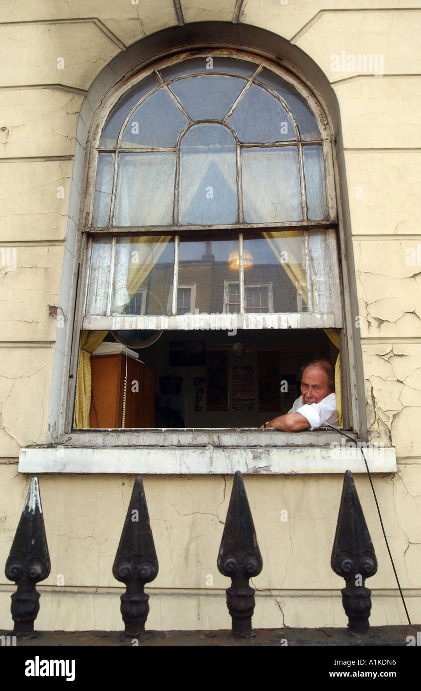 Street scene of elderly man looking out of window and watching the ...