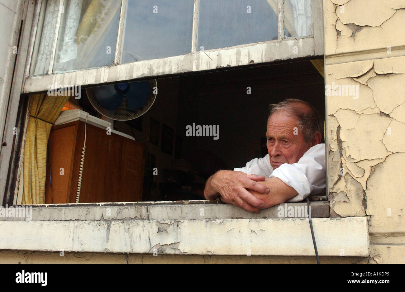 Street scene of man leaning out of window watching the world go by in a ...