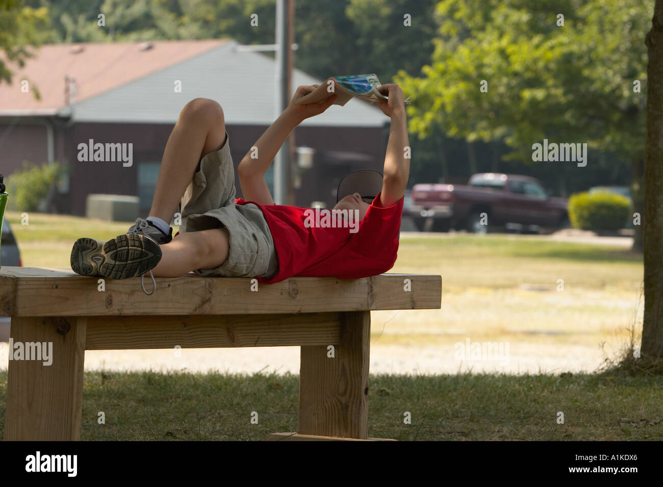 Boy reading while lying on a bench Stock Photo - Alamy