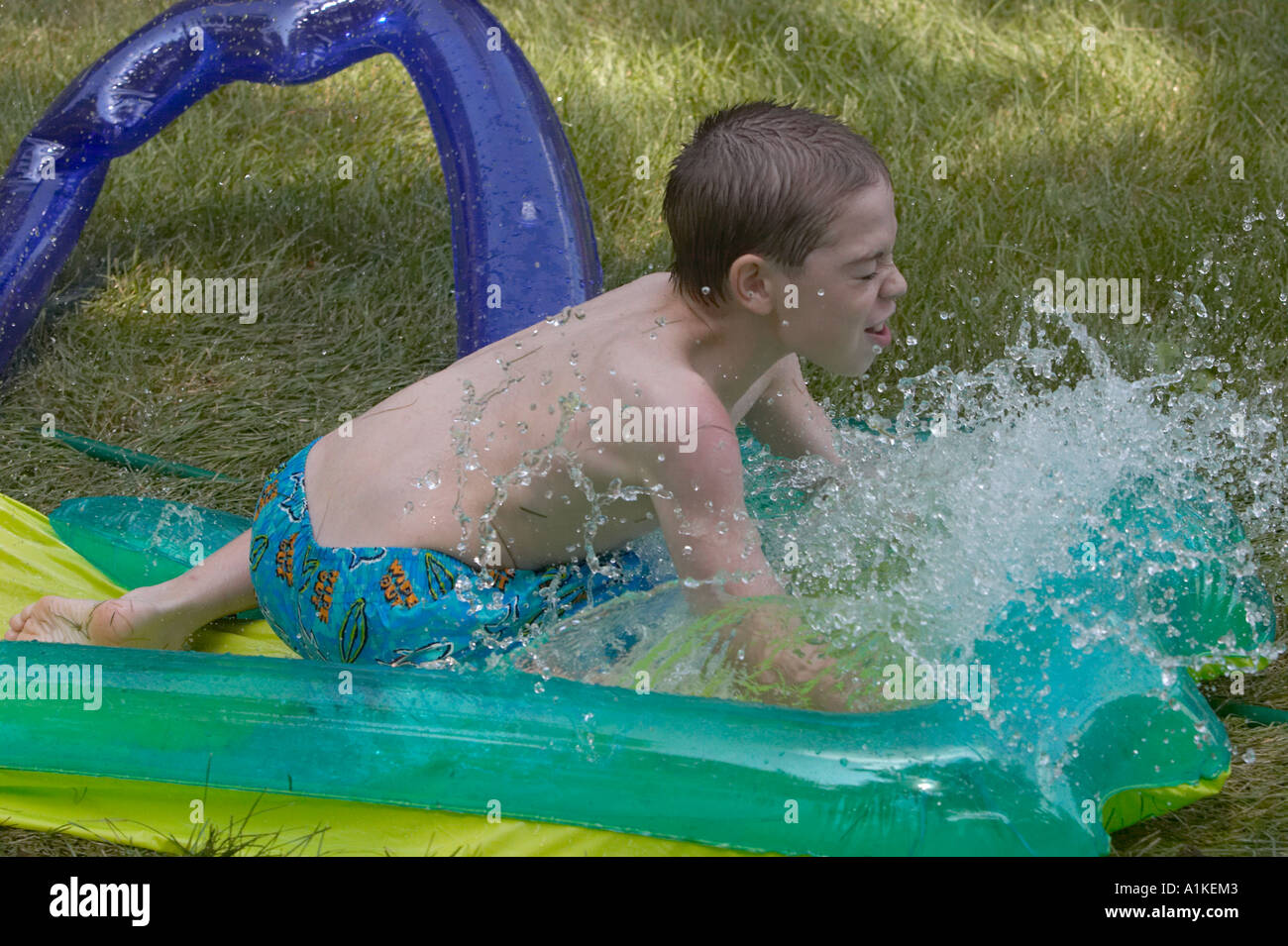 A young boy sliding on a backyard water slide Stock Photo - Alamy