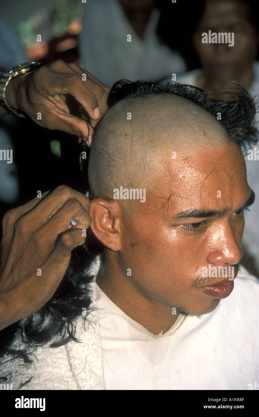 BUDDHISM a young man has his head shaved before entering the monastery ...