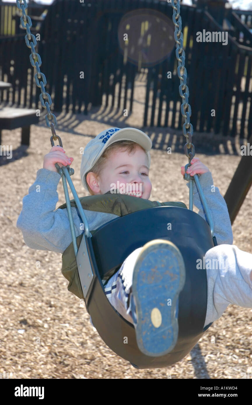 Young three year old smiling boy on a playground swing Stock Photo - Alamy