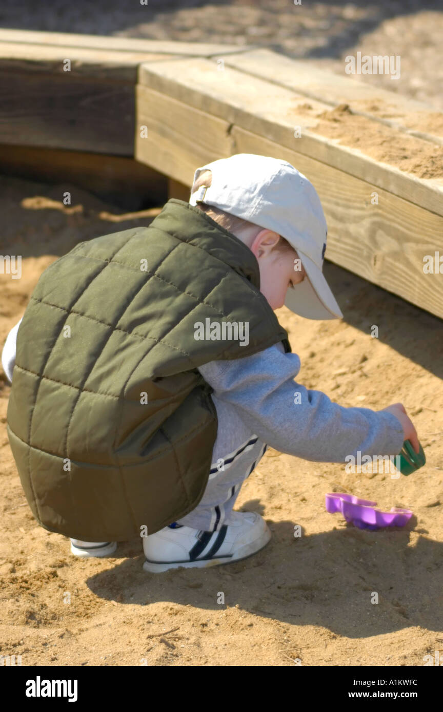 Young three year old boy digging in the sandbox at a playground Stock ...