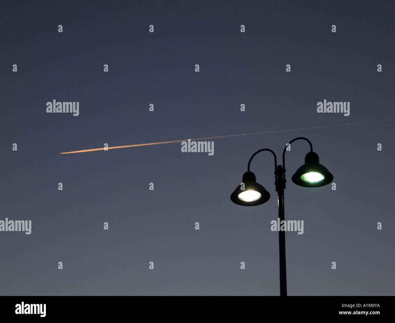Sky and street light with airplane contrail Stock Photo - Alamy
