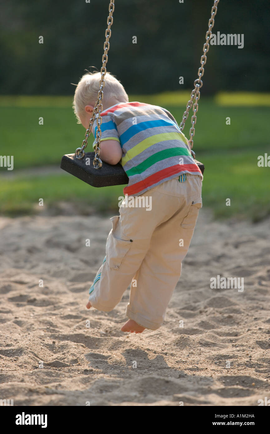 Little bored boy hanging on a swing Stock Photo - Alamy