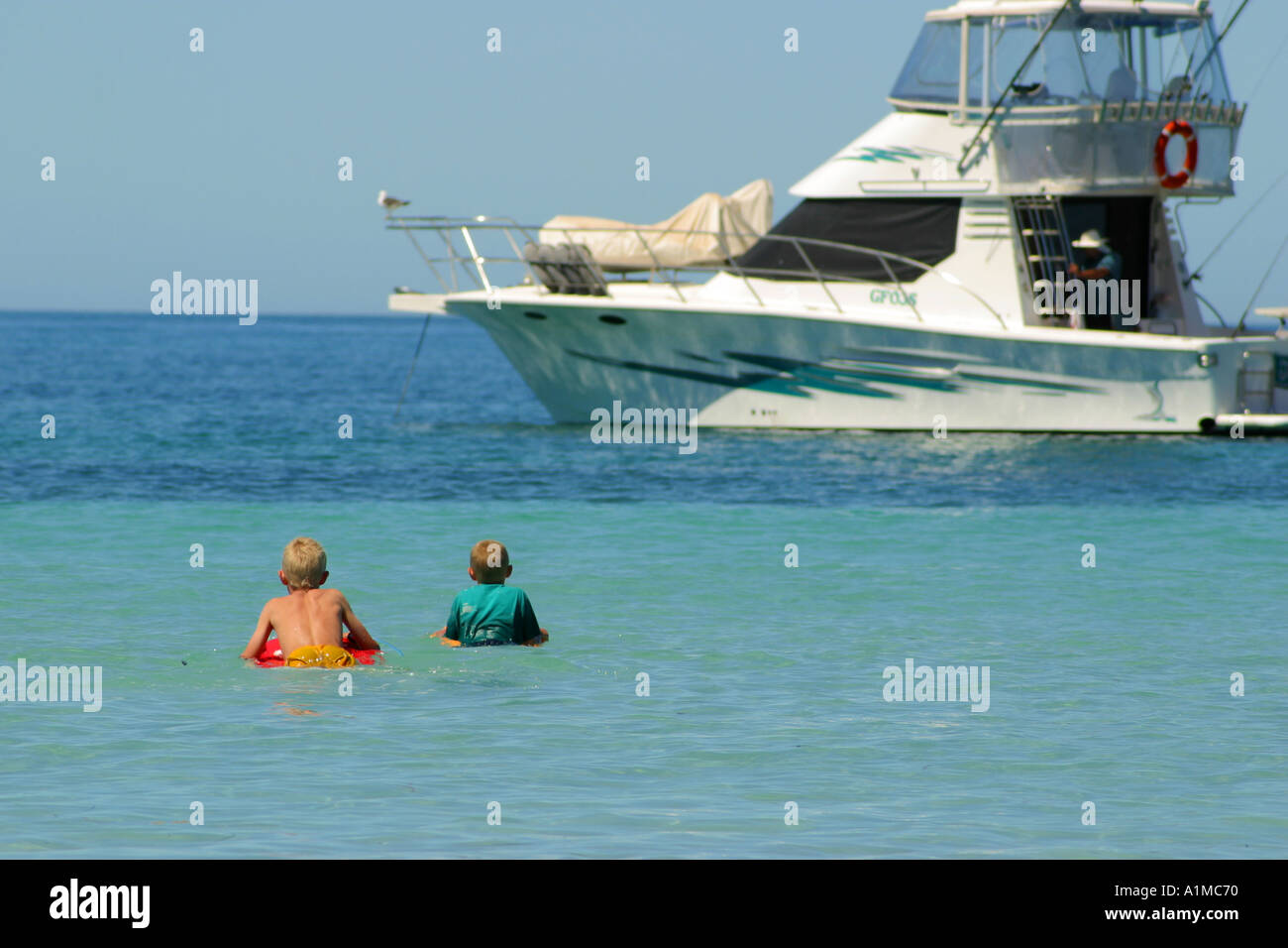 Two boys swimming with cruiser in the background Stock Photo - Alamy